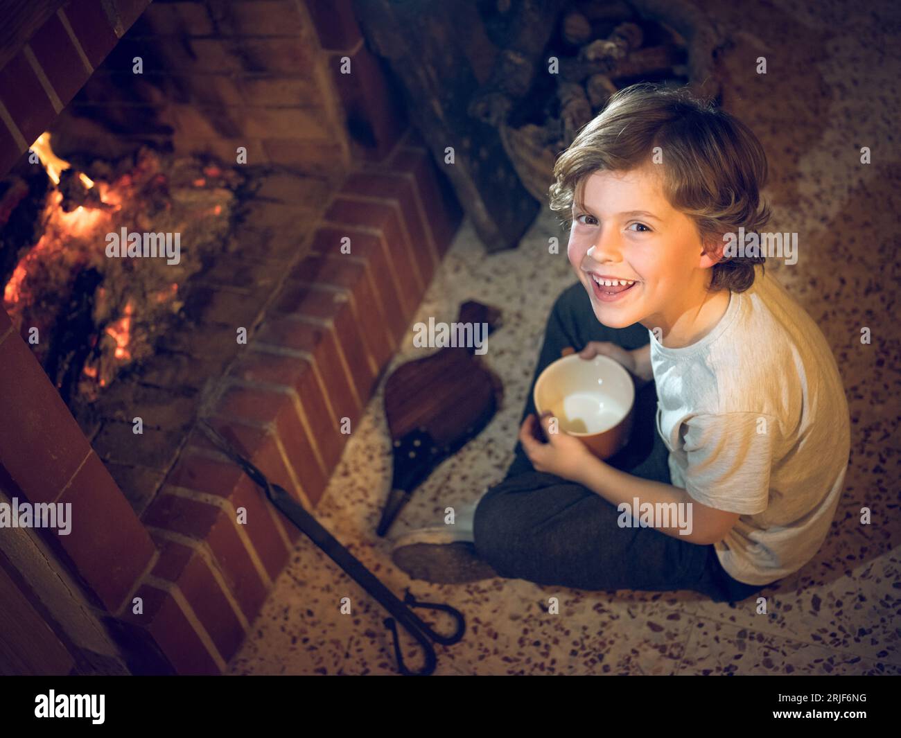 From above of preteen boy sitting with crossed legs and empty mug ...