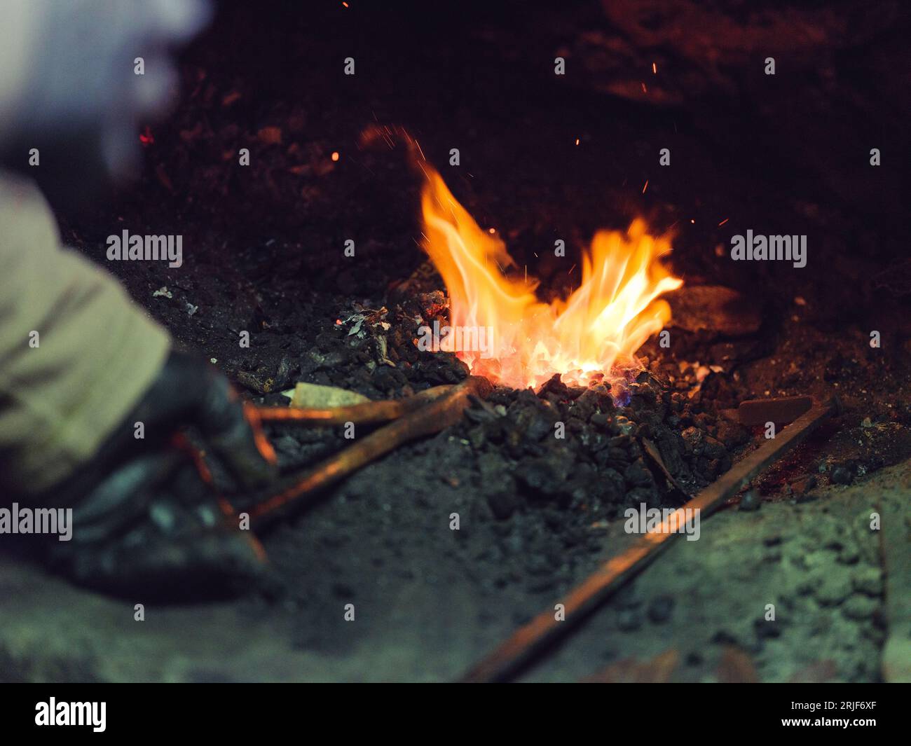 Crop unrecognizable male forger using tongs and heating iron on ...
