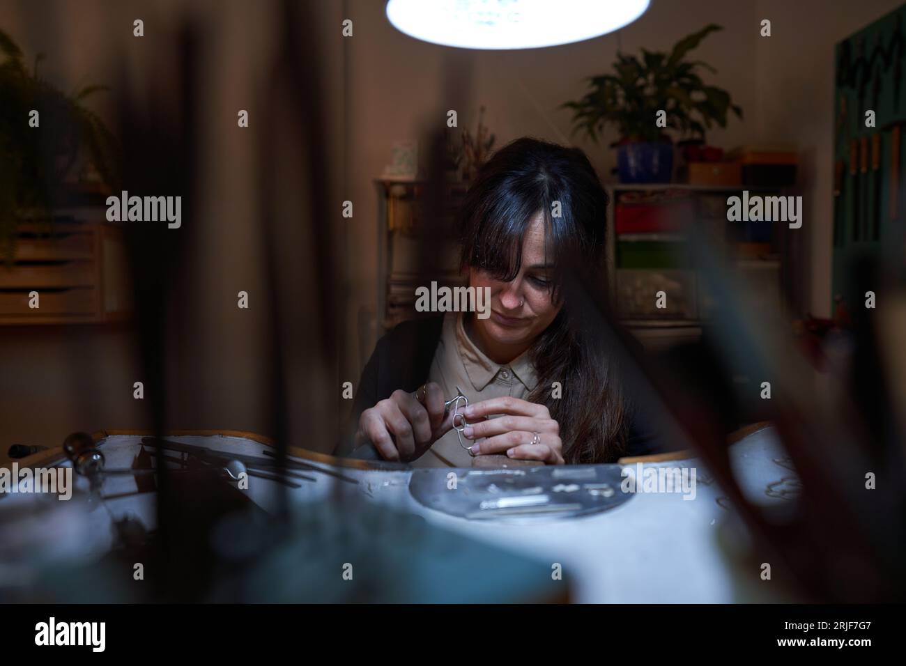 Focused adult ethnic female goldsmith using hand engraving tool while ...