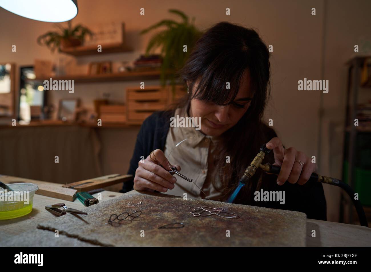 Serious female designer creating metal detail of handmade accessory at ...