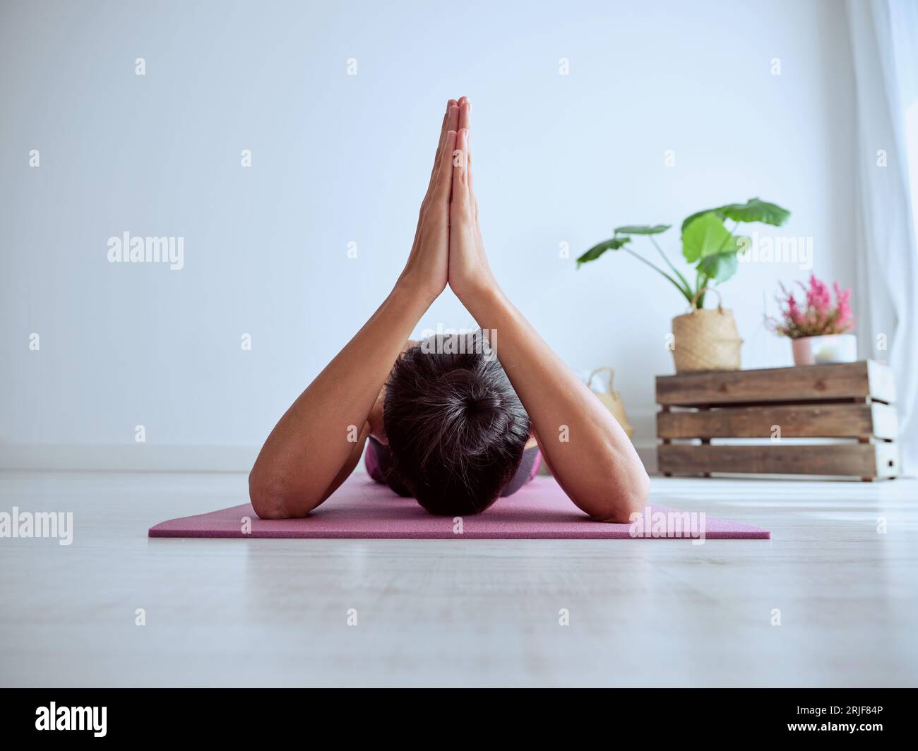 Anonymous female lying on mat with folded hands while doing yoga asana ...
