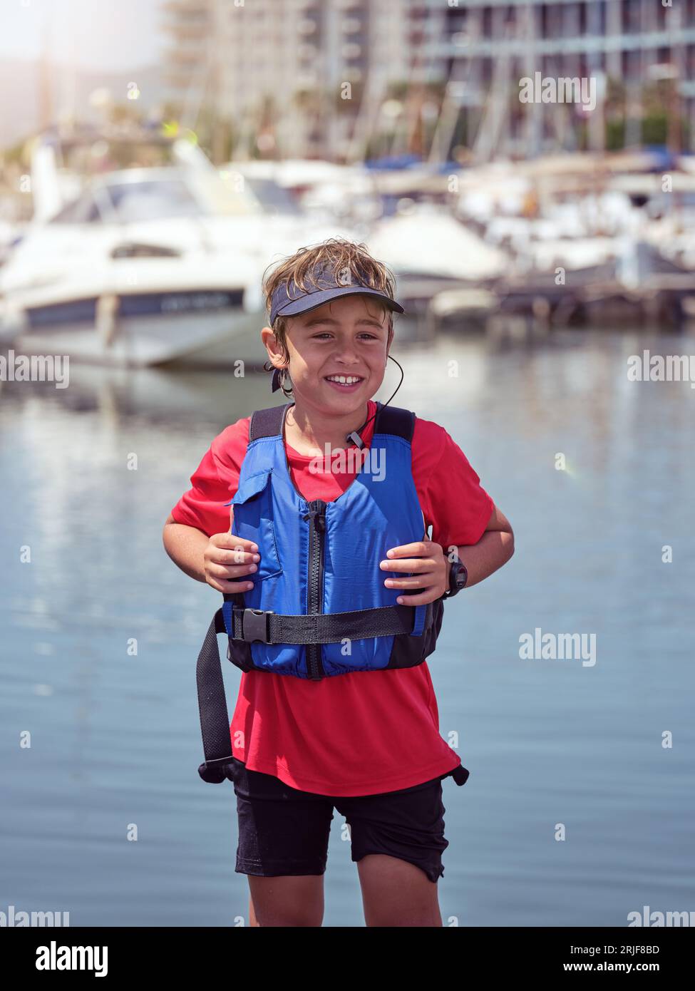 Positive little boy wearing safety equipment and cap standing near ...