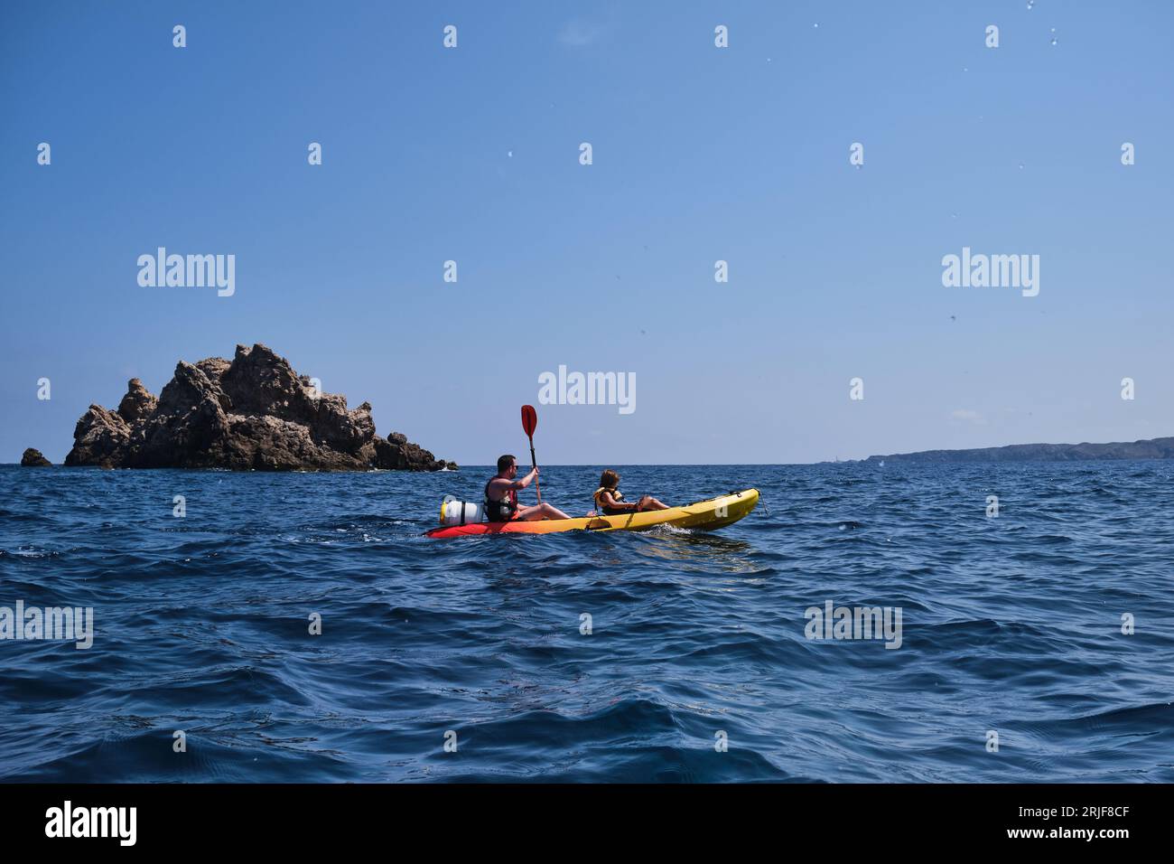 Distant people rowing kayak while floating on rippling sea water ...