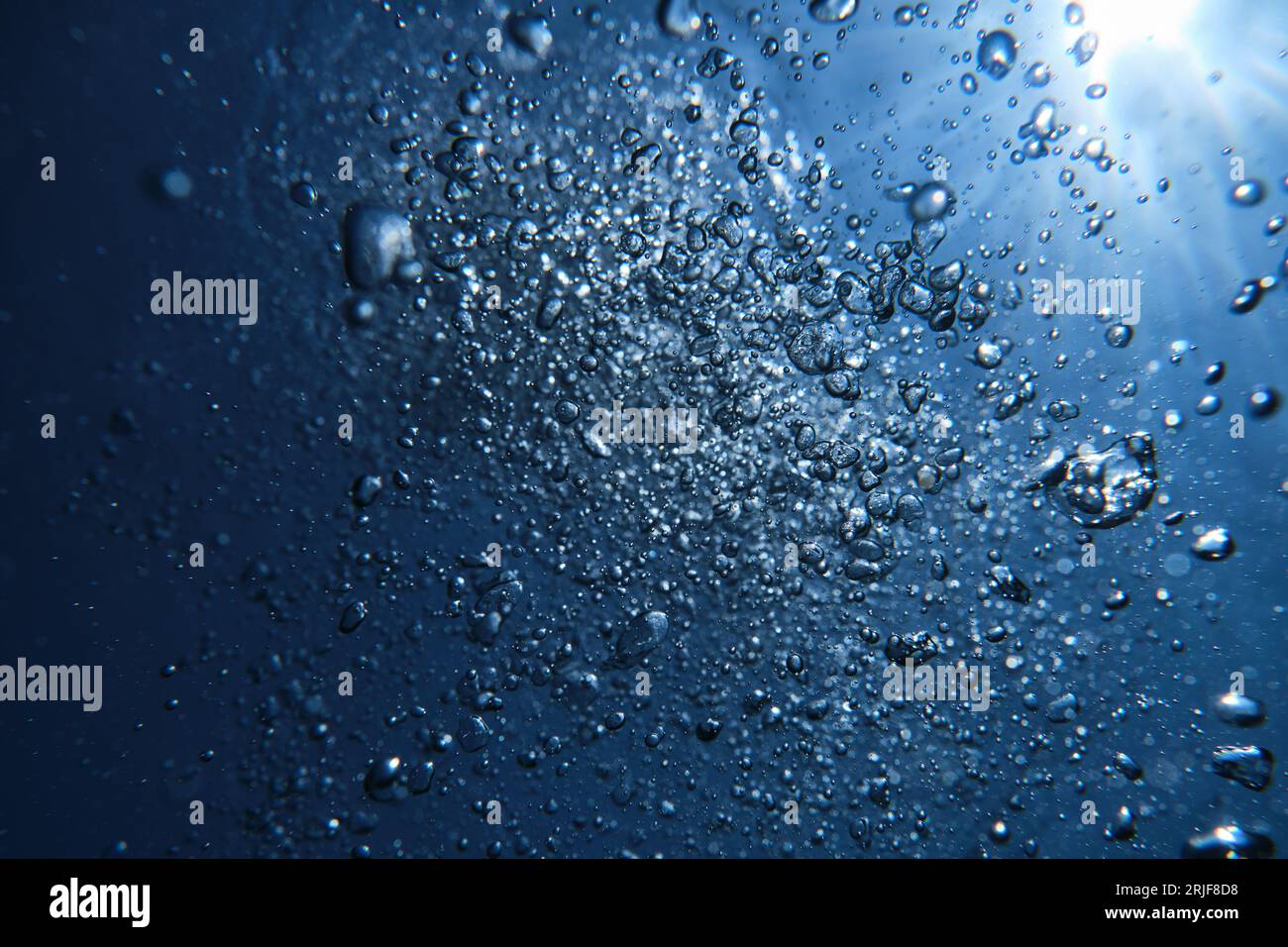 Popping up air bubbles in deep sea with clear blue water and ray of ...