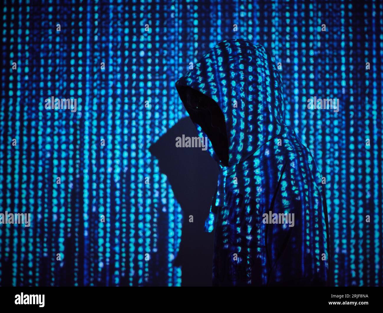 Side View Of Anonymous Hacker In Hoodie Standing In Blue Projection Of