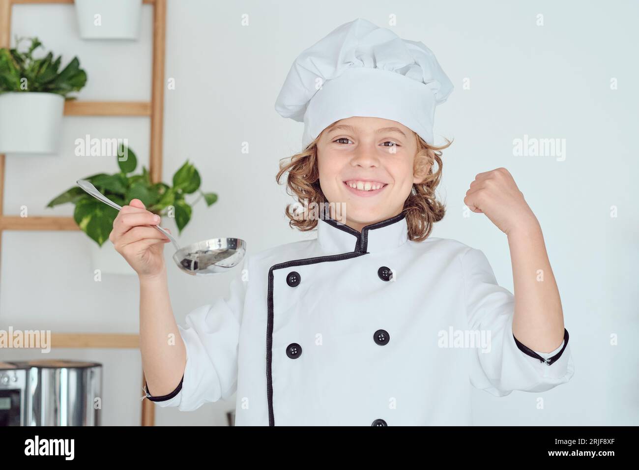 Happy smiling little kid with curly blond hair in white chef hat and ...