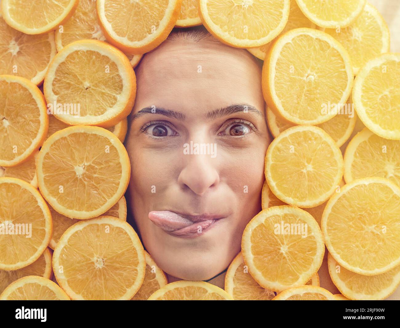 Funny female making grimace and showing tongue through heap of slices ...