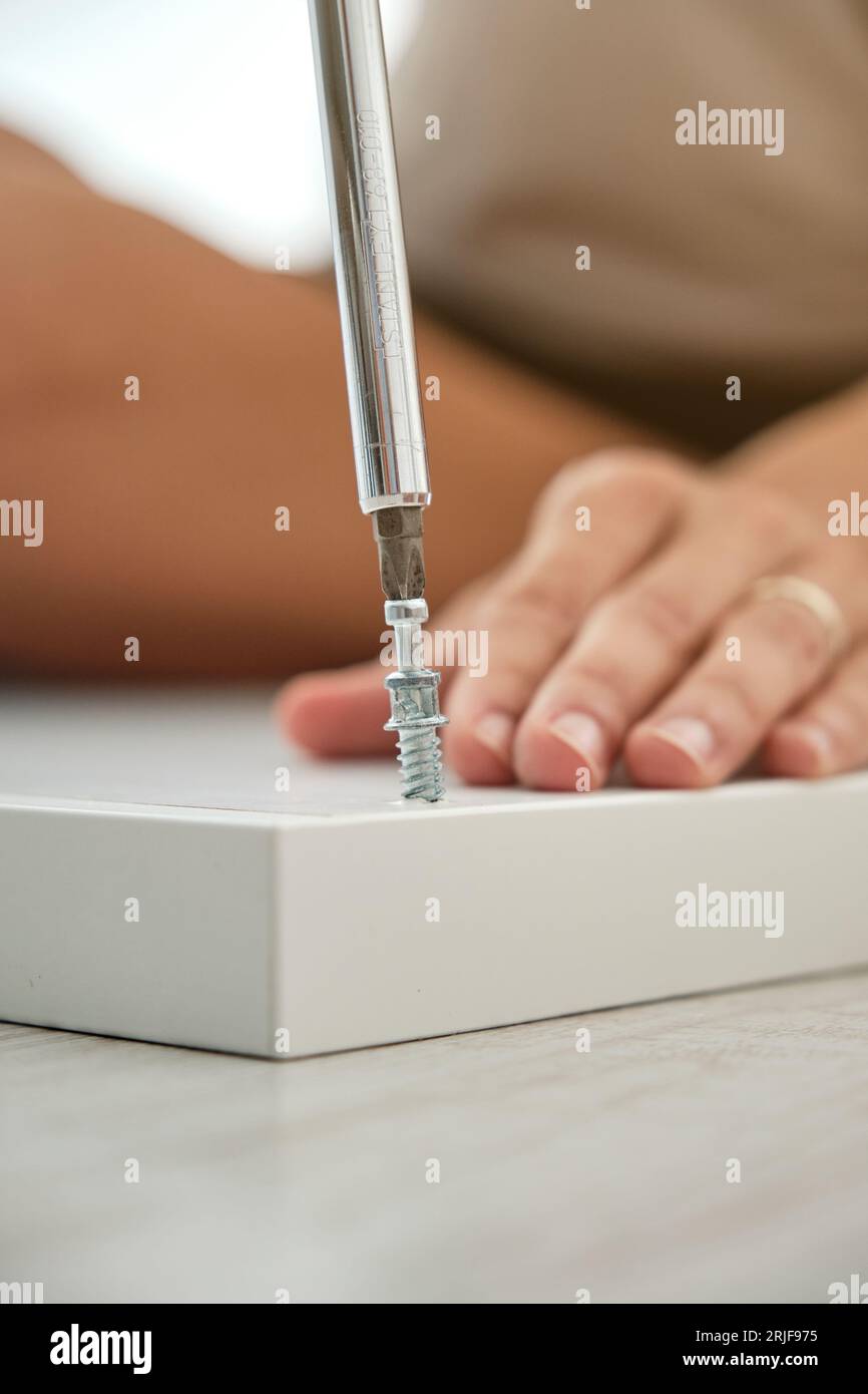 Crop anonymous blurred person sitting on floor and putting screw in ...