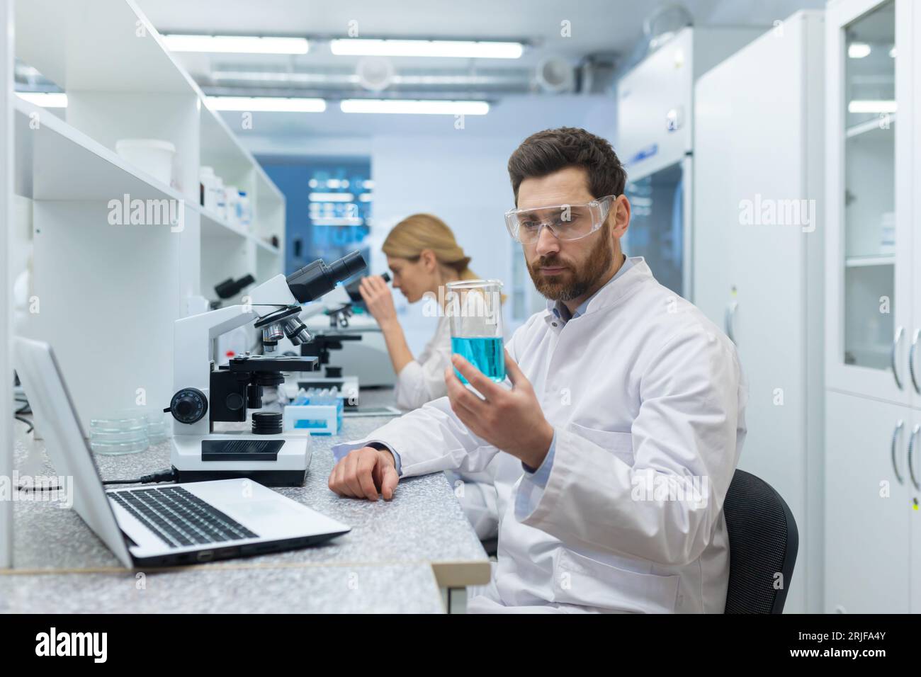 A young male scientist works in a laboratory. He sits at the work table ...