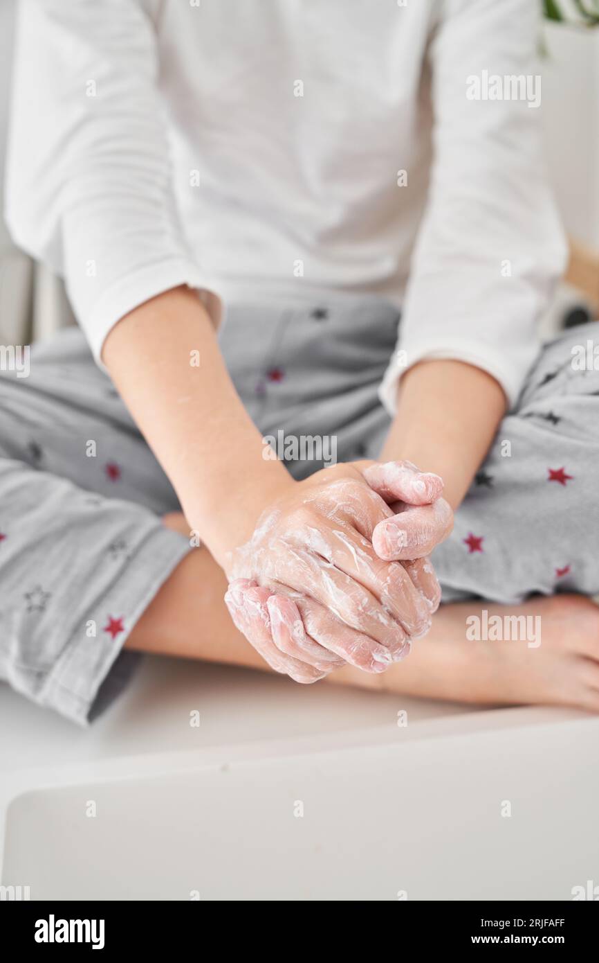 Crop unrecognizable barefoot boy in pajama sitting with crossed legs ...