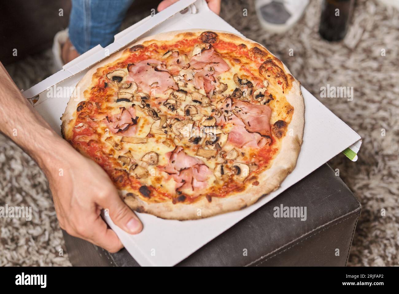 From above of crop anonymous male holding carton box with pizza to go ...