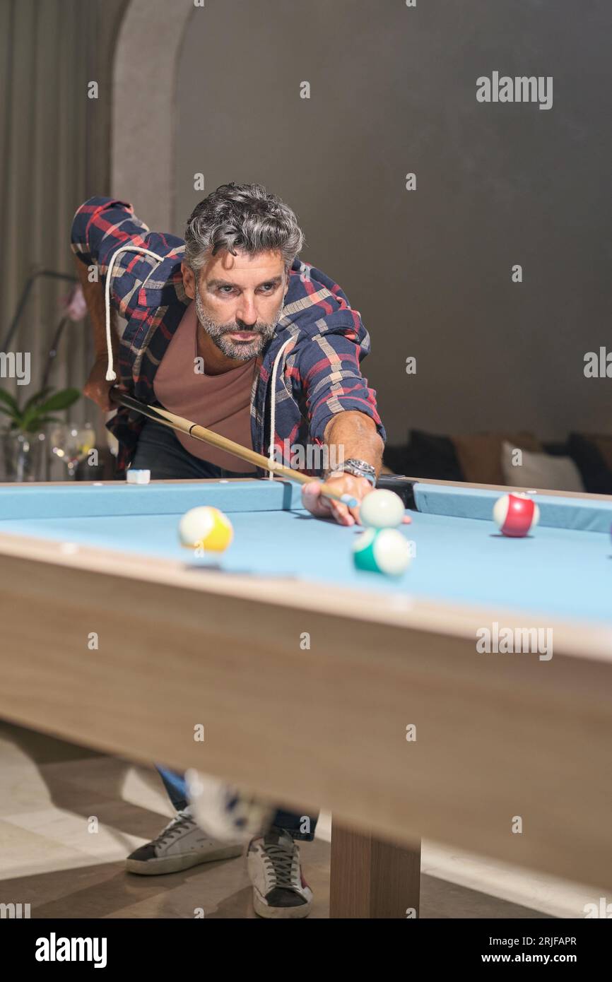 Serious middle aged bearded man with stylish haircut playing billiards ...