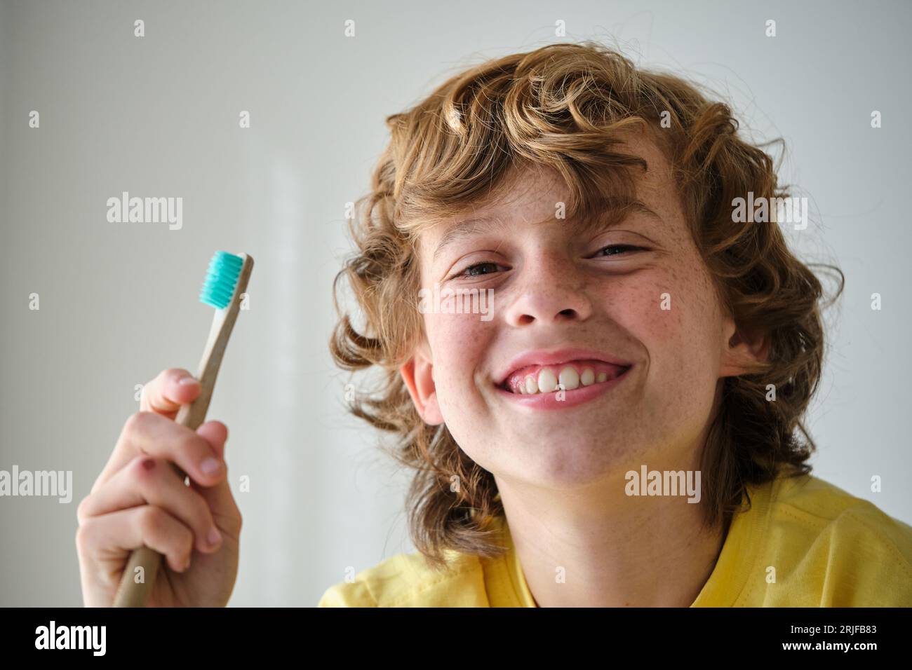 Cheerful kid with freckled face skin and brown wavy hair looking at ...