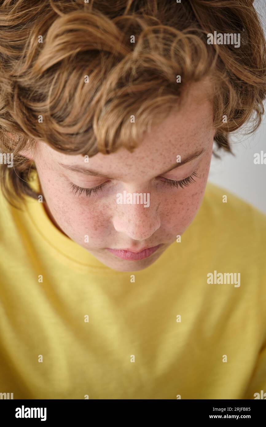 Crop sad child in yellow apparel with freckles on face skin and wavy ...