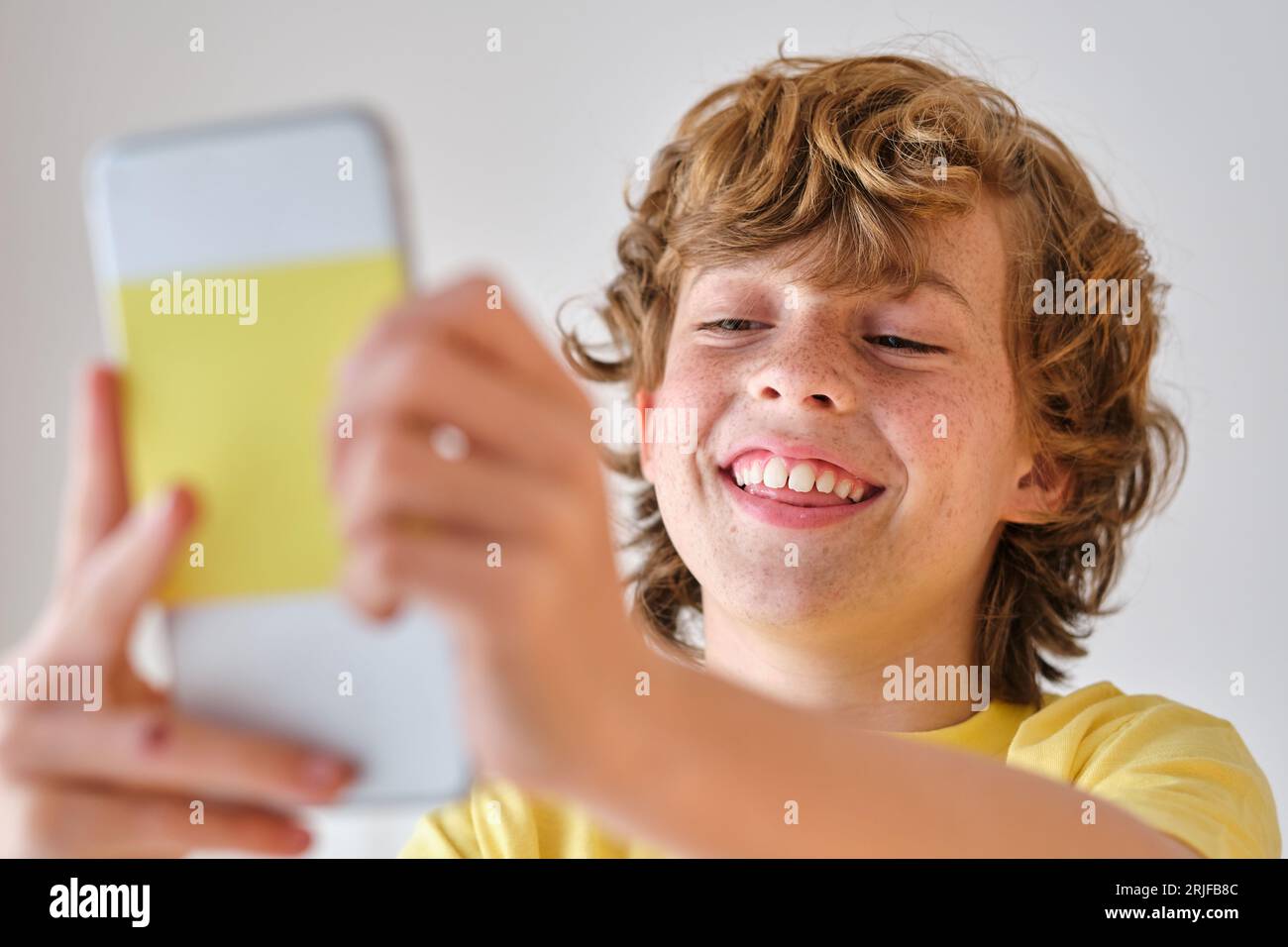 Smiling kid with freckled face skin and brown hair taking self portrait ...