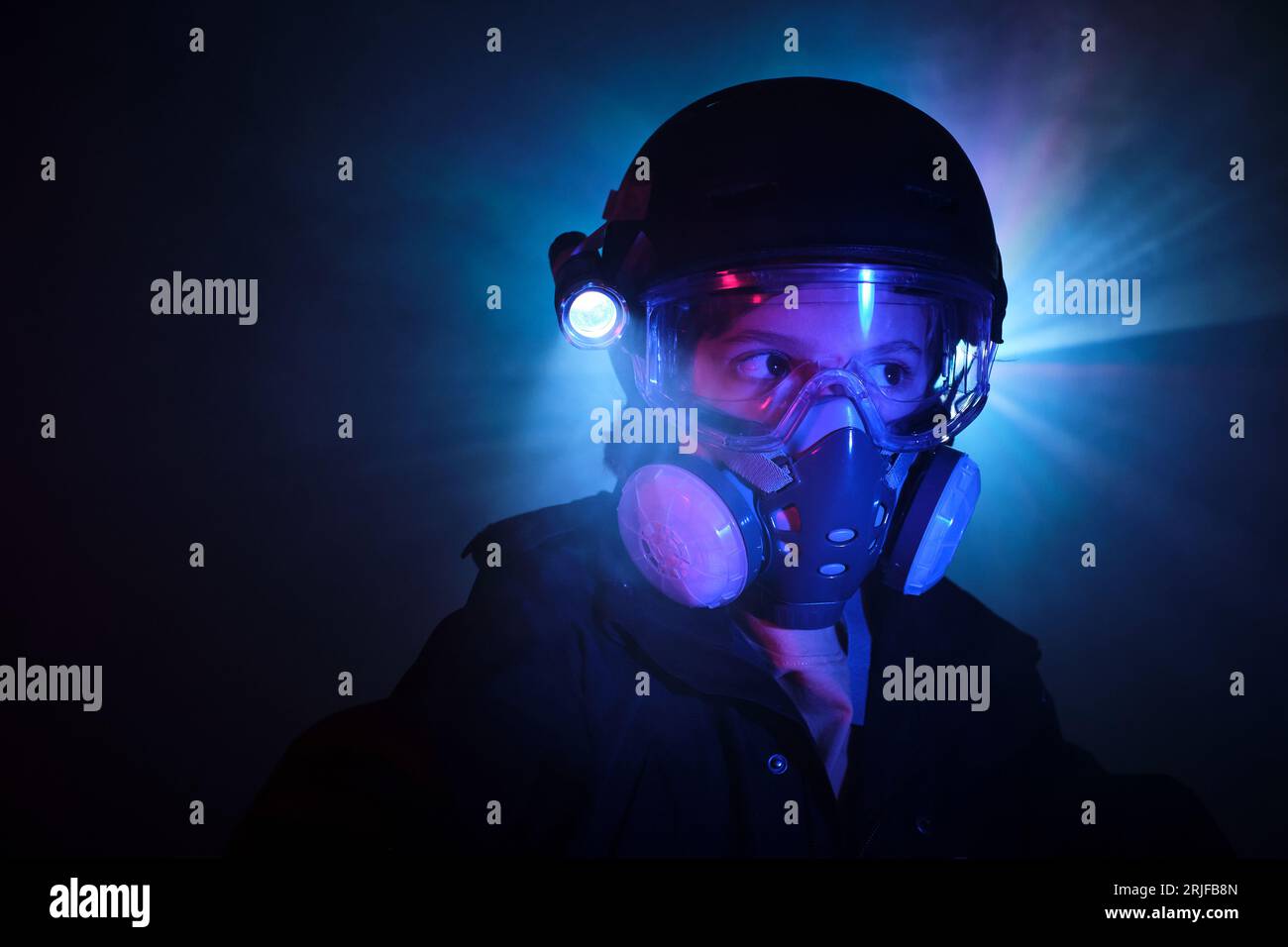Robber in protective respirator with shining flashlight observing ...