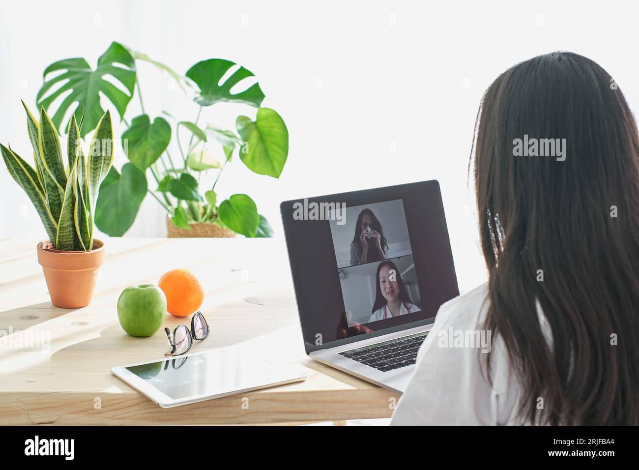 Back view of Asian female medic conducting online consultation with ...