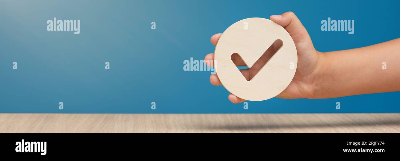 Hand holding check mark icon, banner with wooden check mark icon in ...