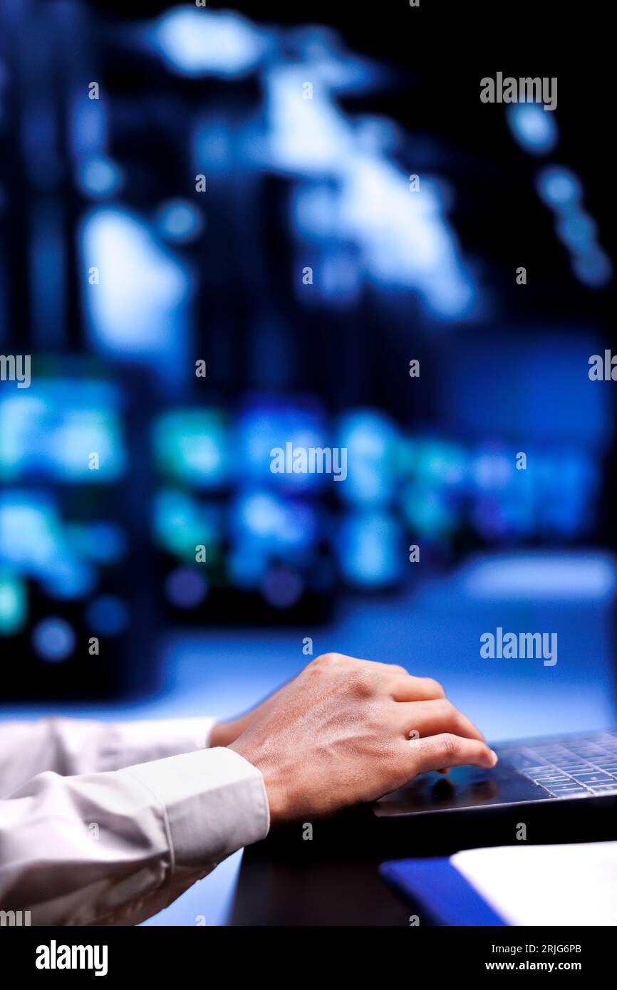 Serviceman using laptop to examine server rigs for power fluctuations ...