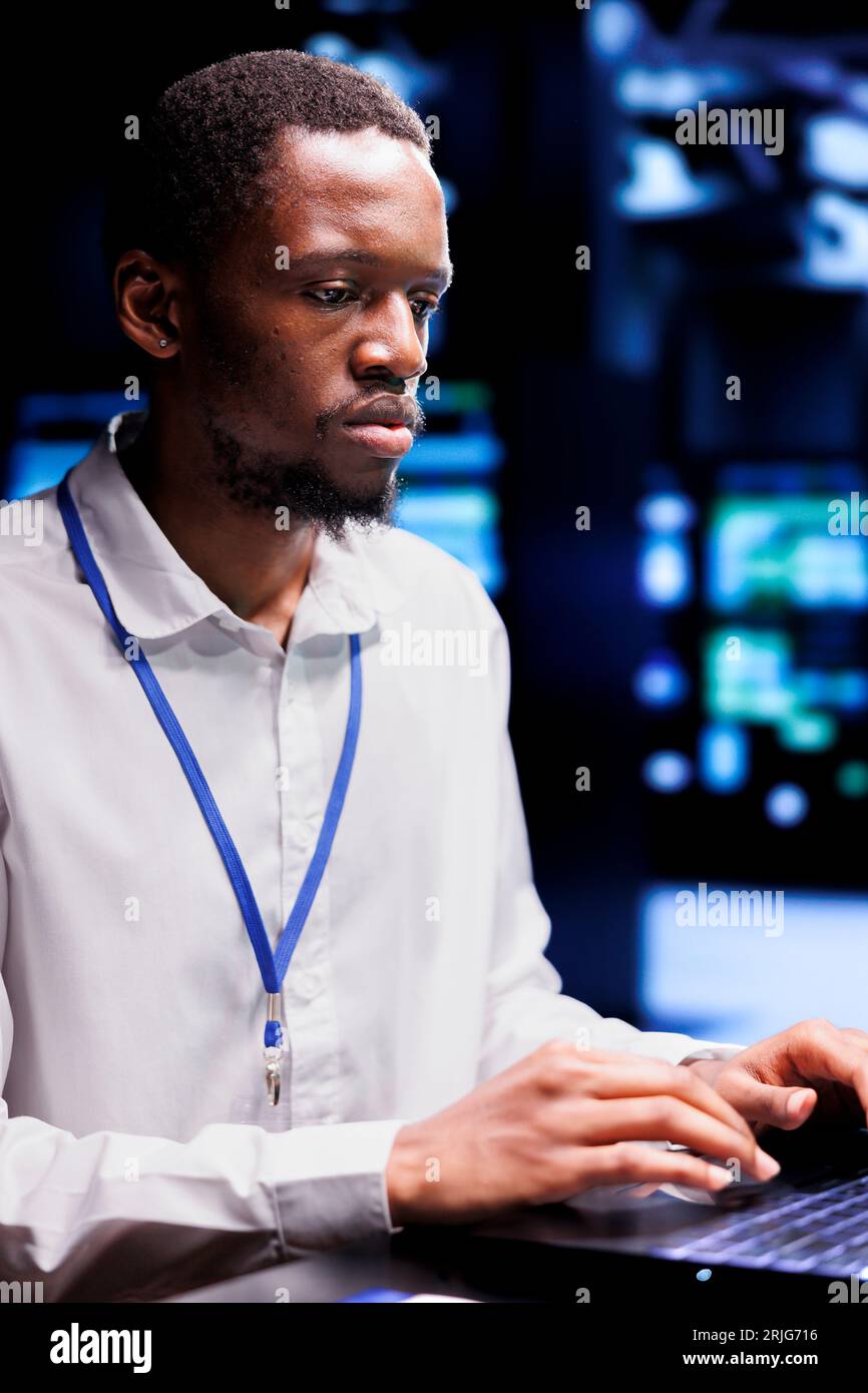 African american IT developer in data center using laptop to set up ...