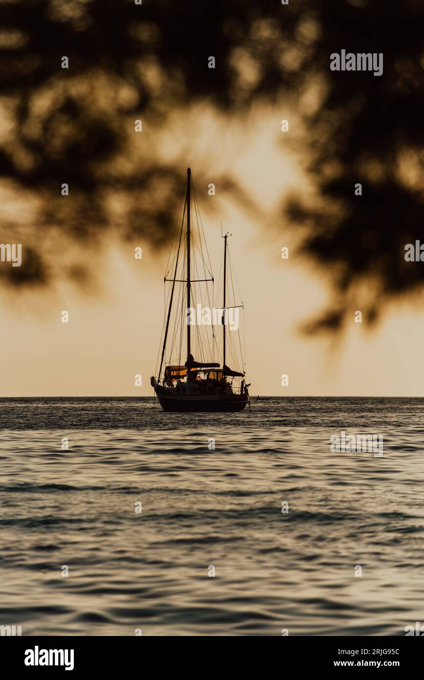 A ship sails on the open sea during sunset, as the glowing orange sky ...