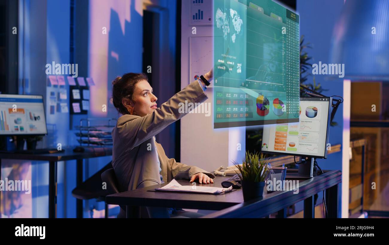 Accountant imputing revenue figures on computer in office during nightshift, visualizing them ...