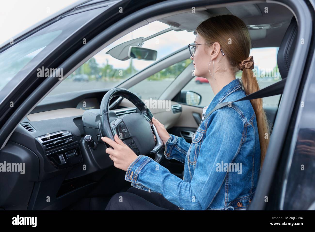 Teenage girl driver in glasses sitting behind wheel of car Stock Photo ...
