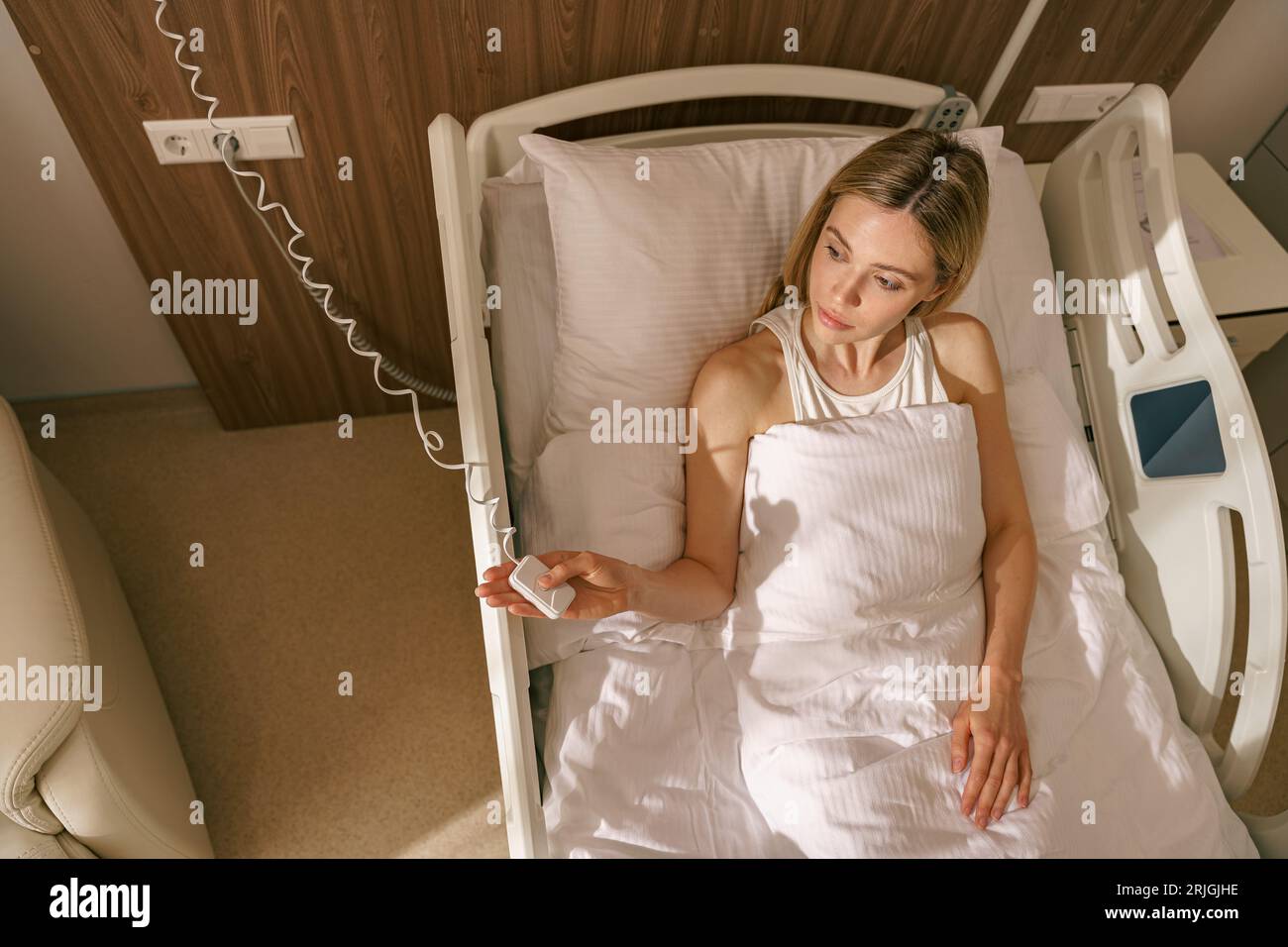Top view of woman patient holding emergency call button while lying in ...