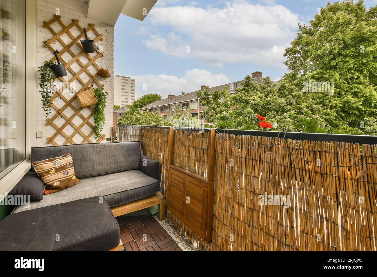 an outside area with a couch and some plants on the side of the balcony ...