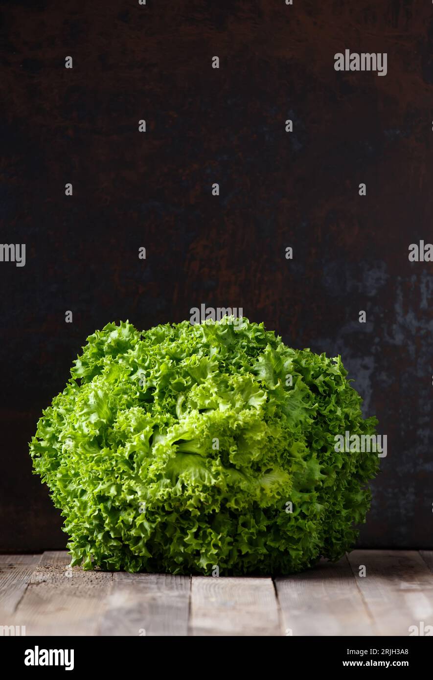 Big bunch of fresh green lettuce leaves on a wooden table and dark ...