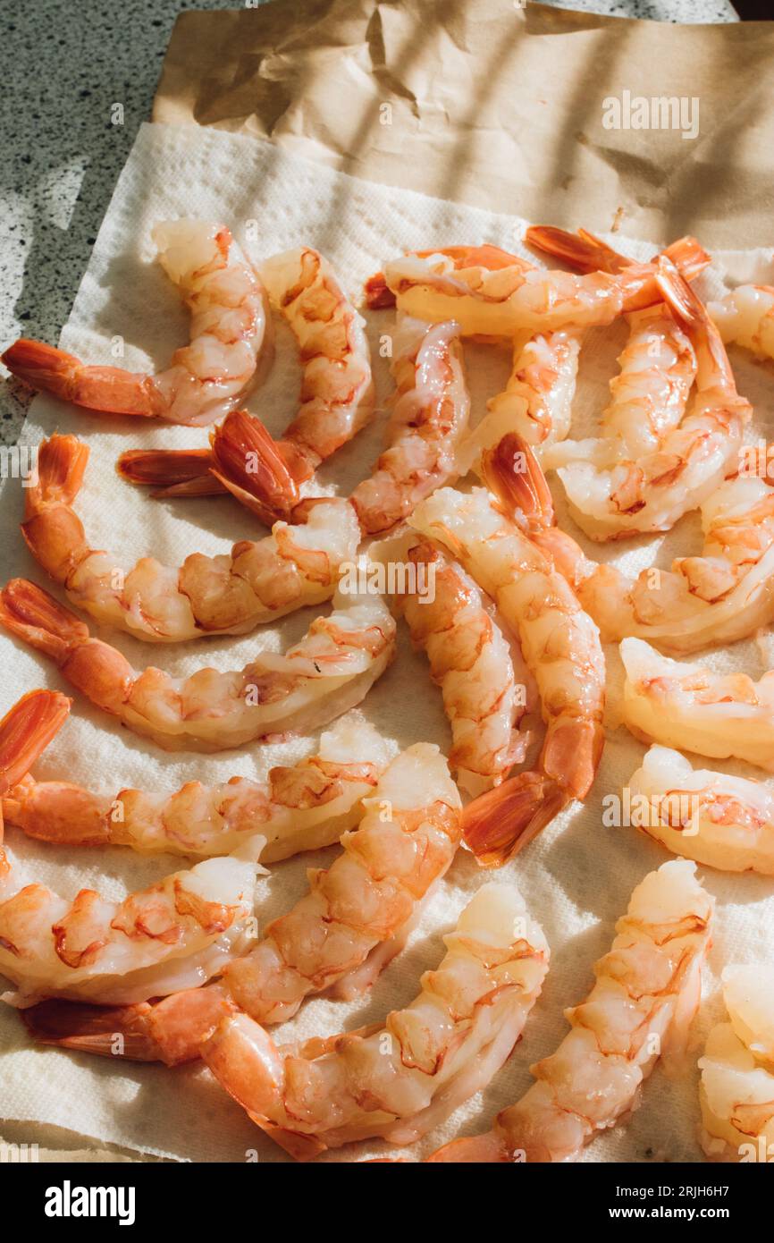 raw de-shelled prawns shrimp with tails on paper towel in the sun Stock ...