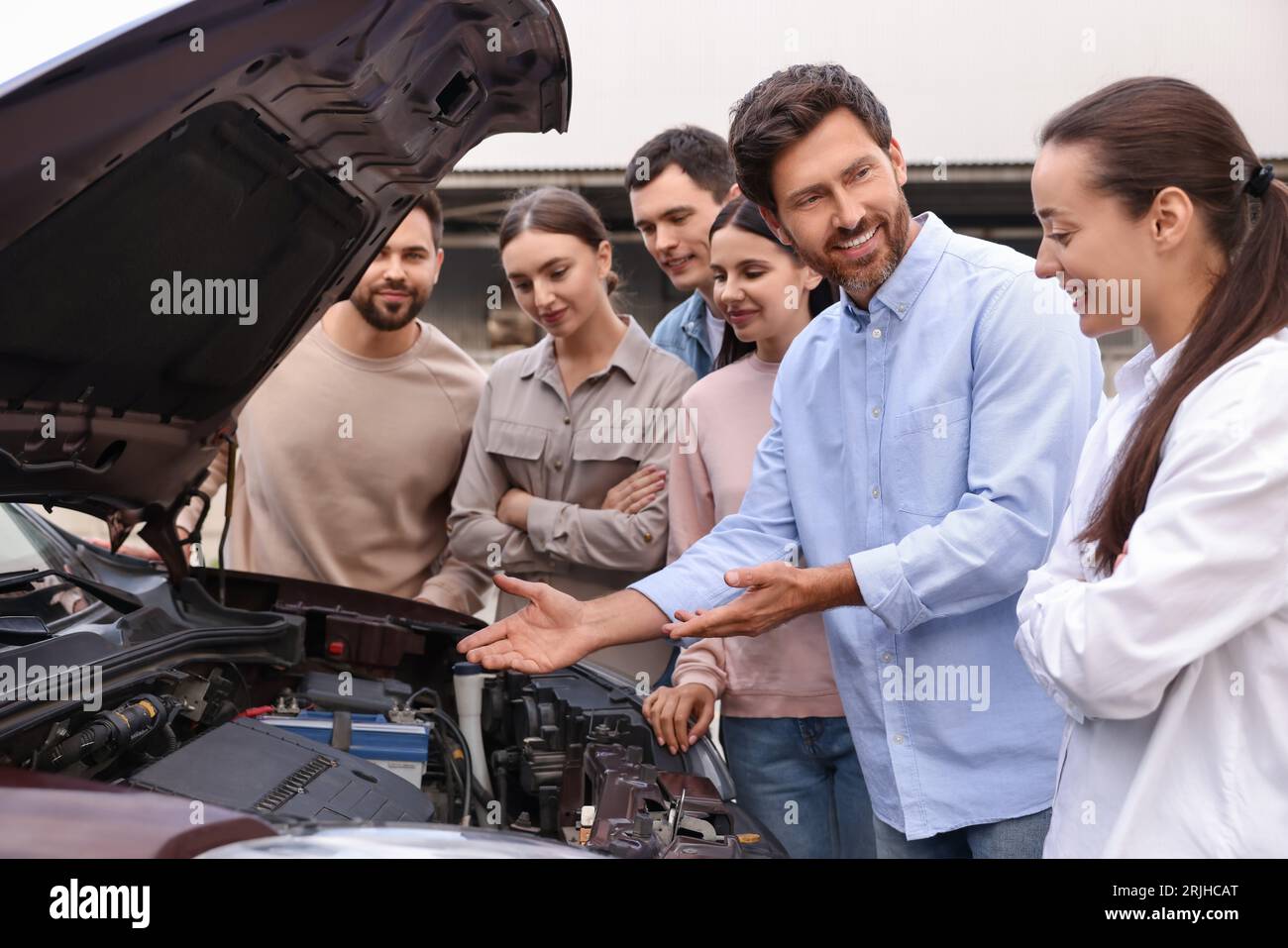 Driving school. Teacher explaining car engine to group outdoors Stock ...