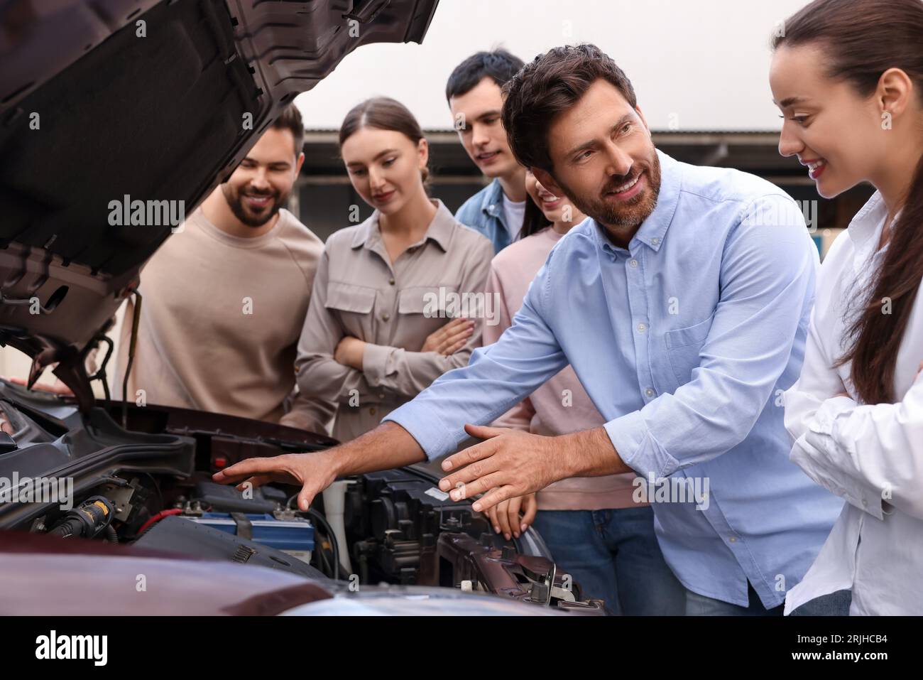 Driving school. Teacher explaining car engine to group outdoors Stock ...