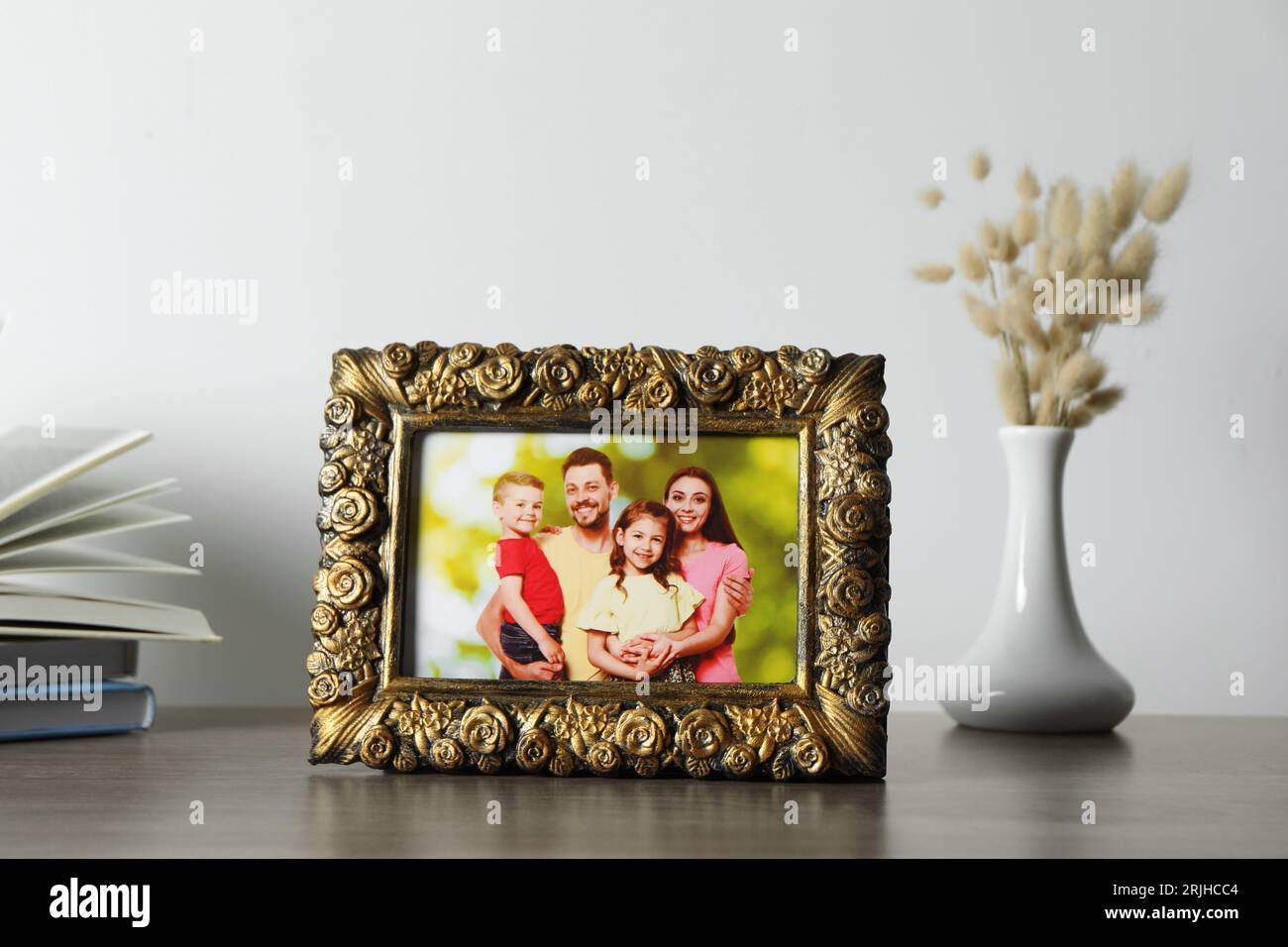 Vintage square frame with family photo, books and vase of dry flowers ...