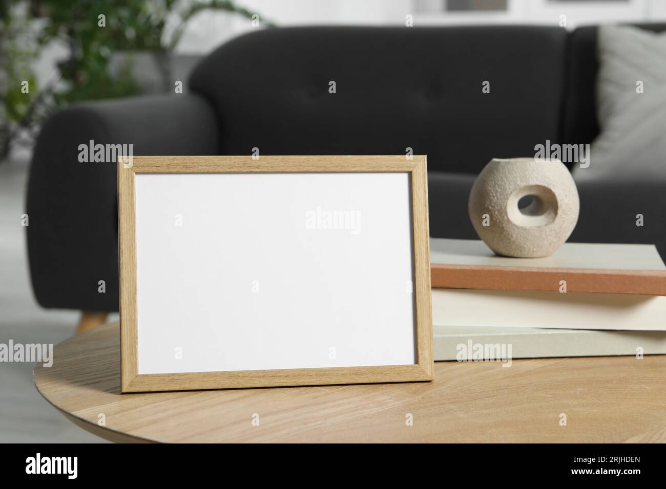 Empty square frame and books on coffee table indoors Stock Photo - Alamy