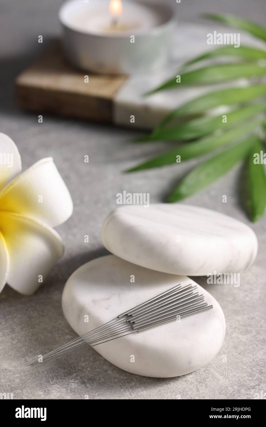Stones with acupuncture needles and lily flower on grey table Stock ...