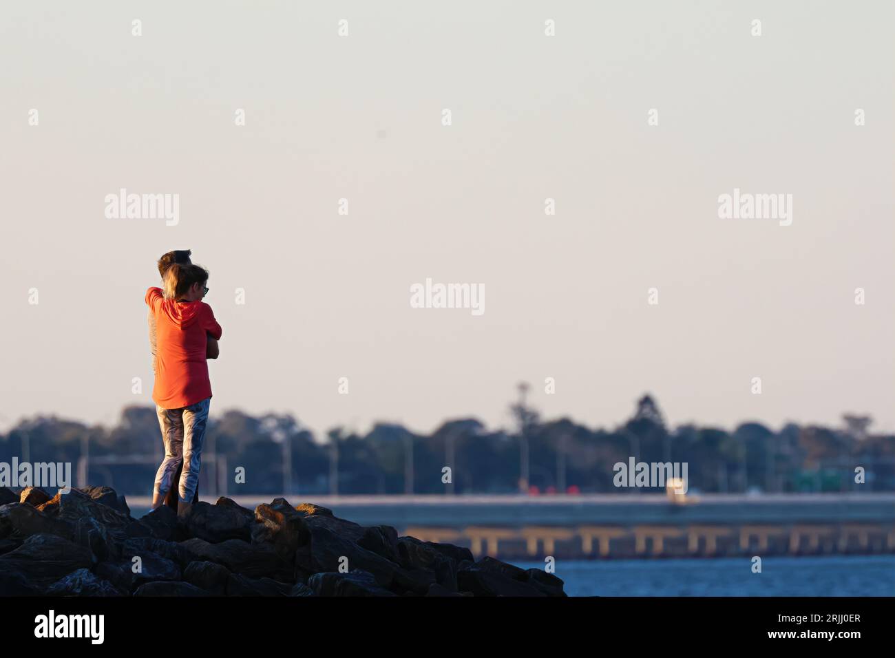 Random people hugging along the ocean shore, looking away from the ...