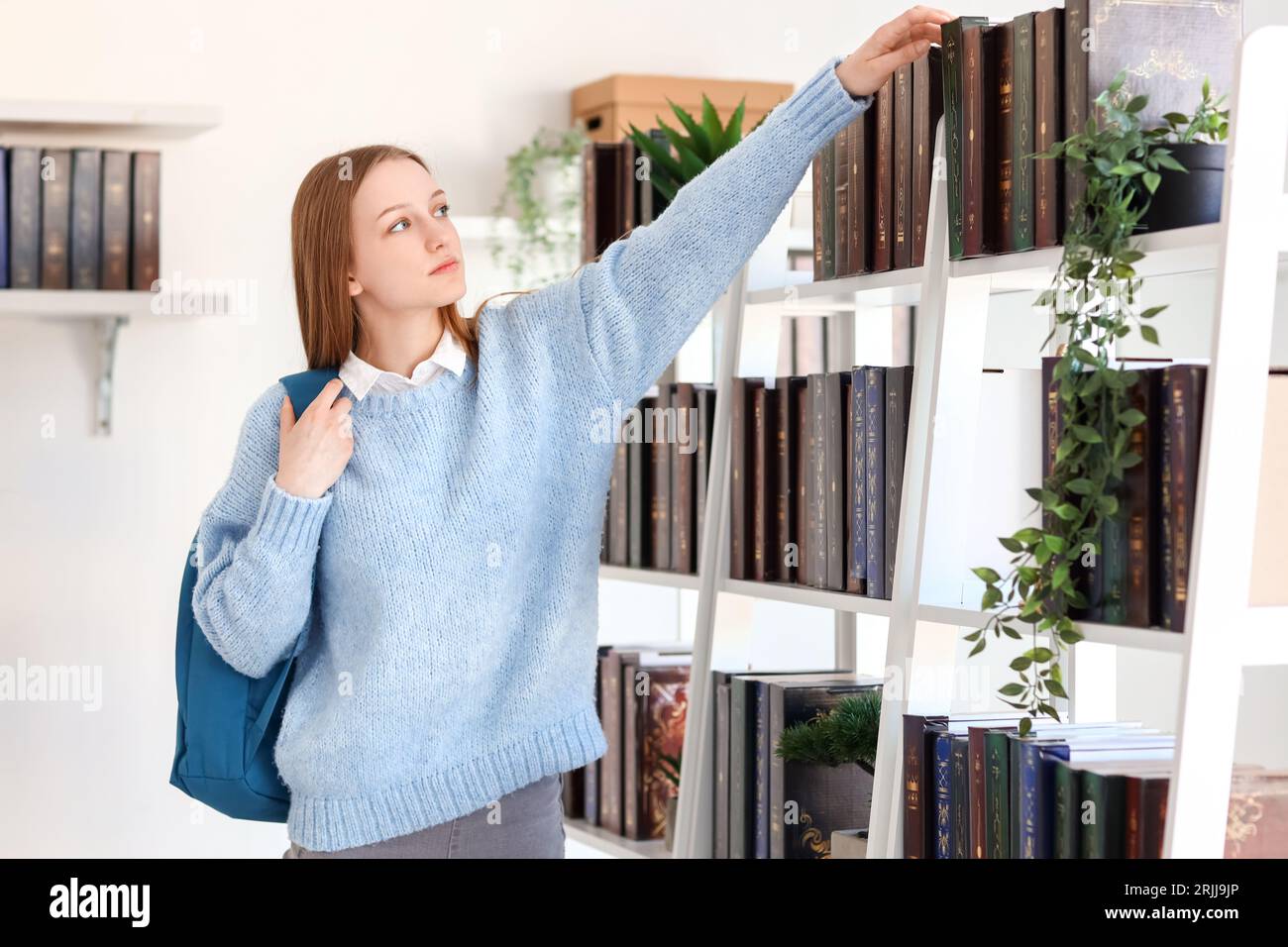 Female student taking book from shelf in library Stock Photo - Alamy
