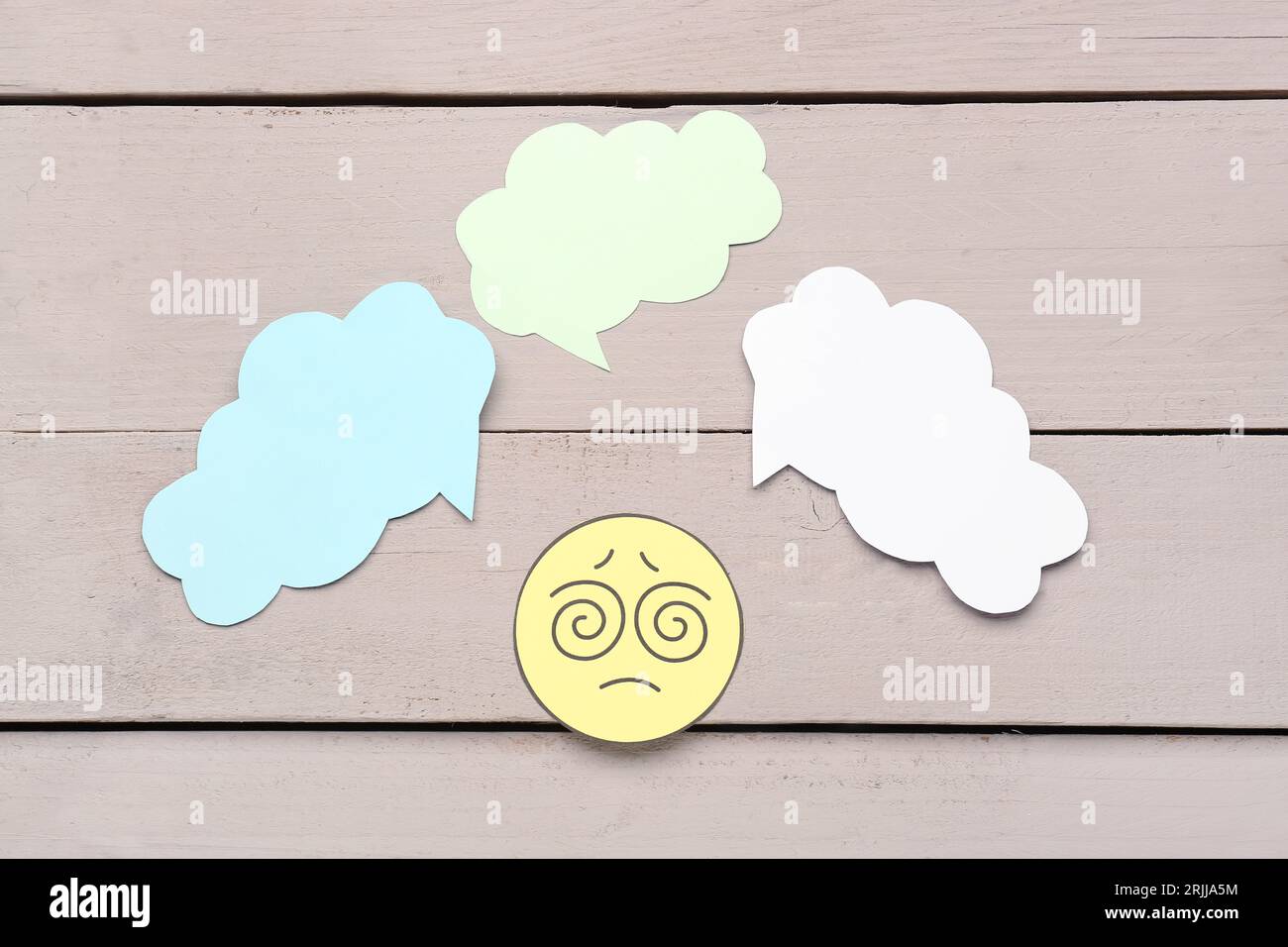 Confused paper face with blank speech bubbles on grey wooden background ...
