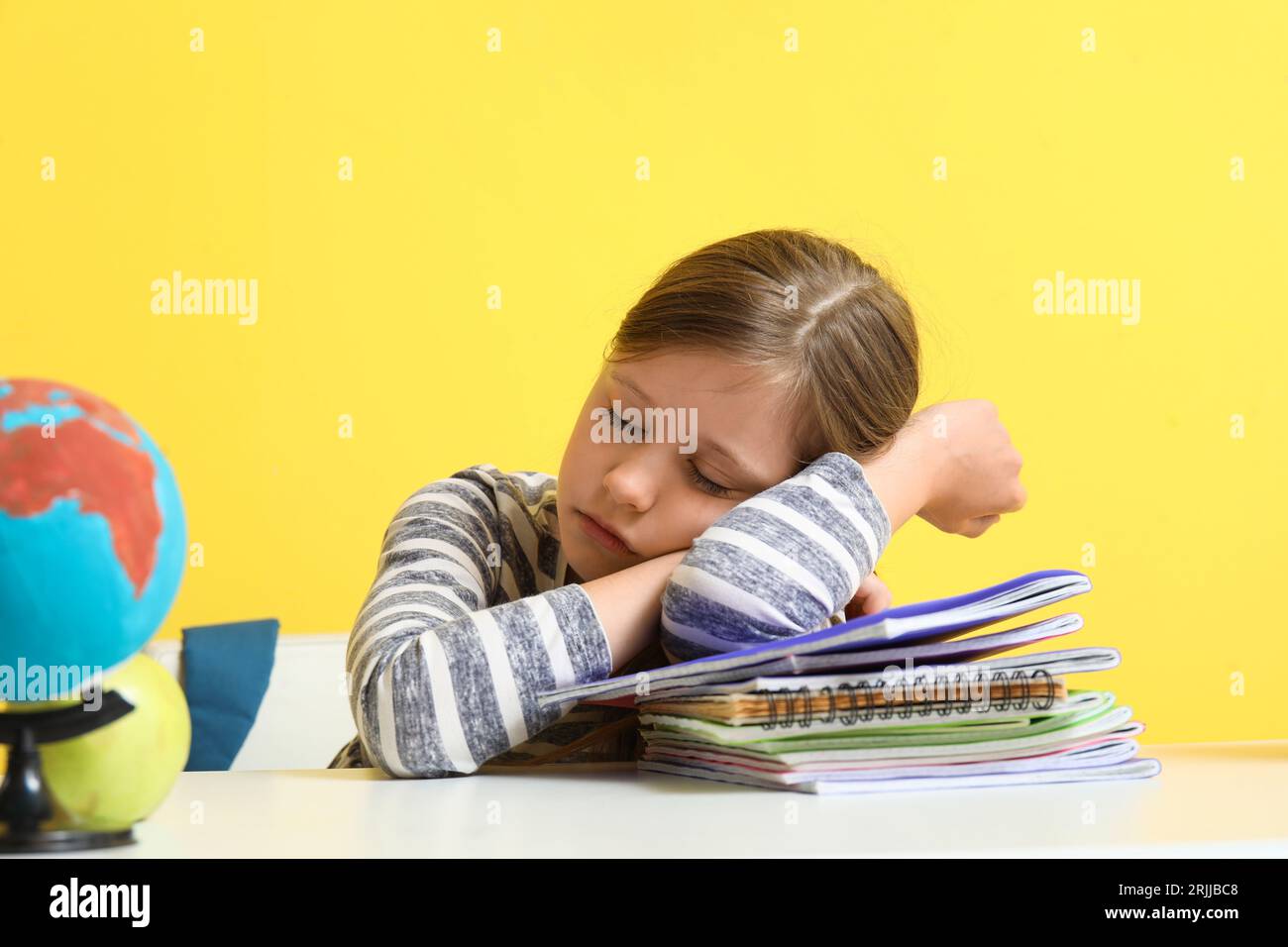 Little girl sleeping at table on yellow background Stock Photo - Alamy