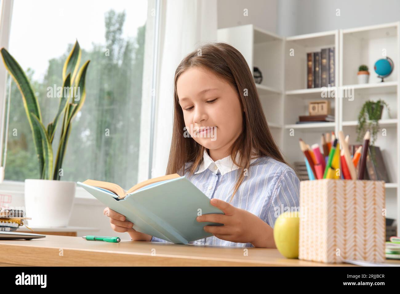 Cute little girl reading schoolbook at home Stock Photo - Alamy