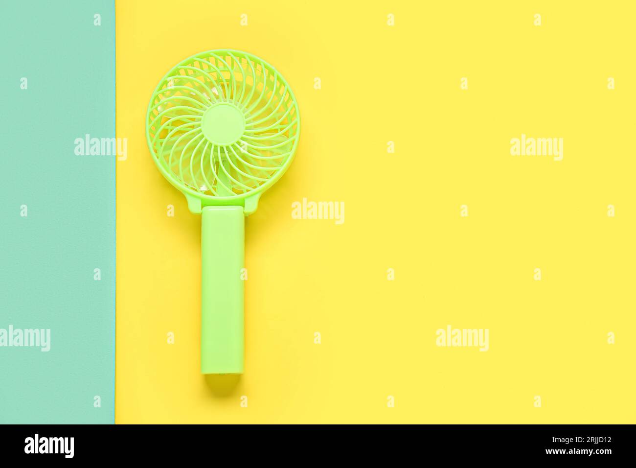 Small green electric fan on color background Stock Photo - Alamy