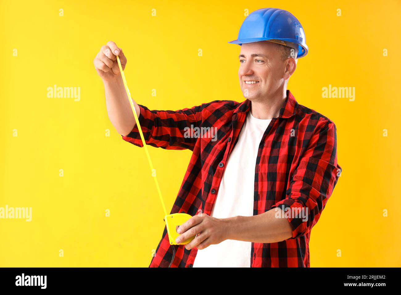 Mature worker with tape measure on yellow background. Labor Day ...