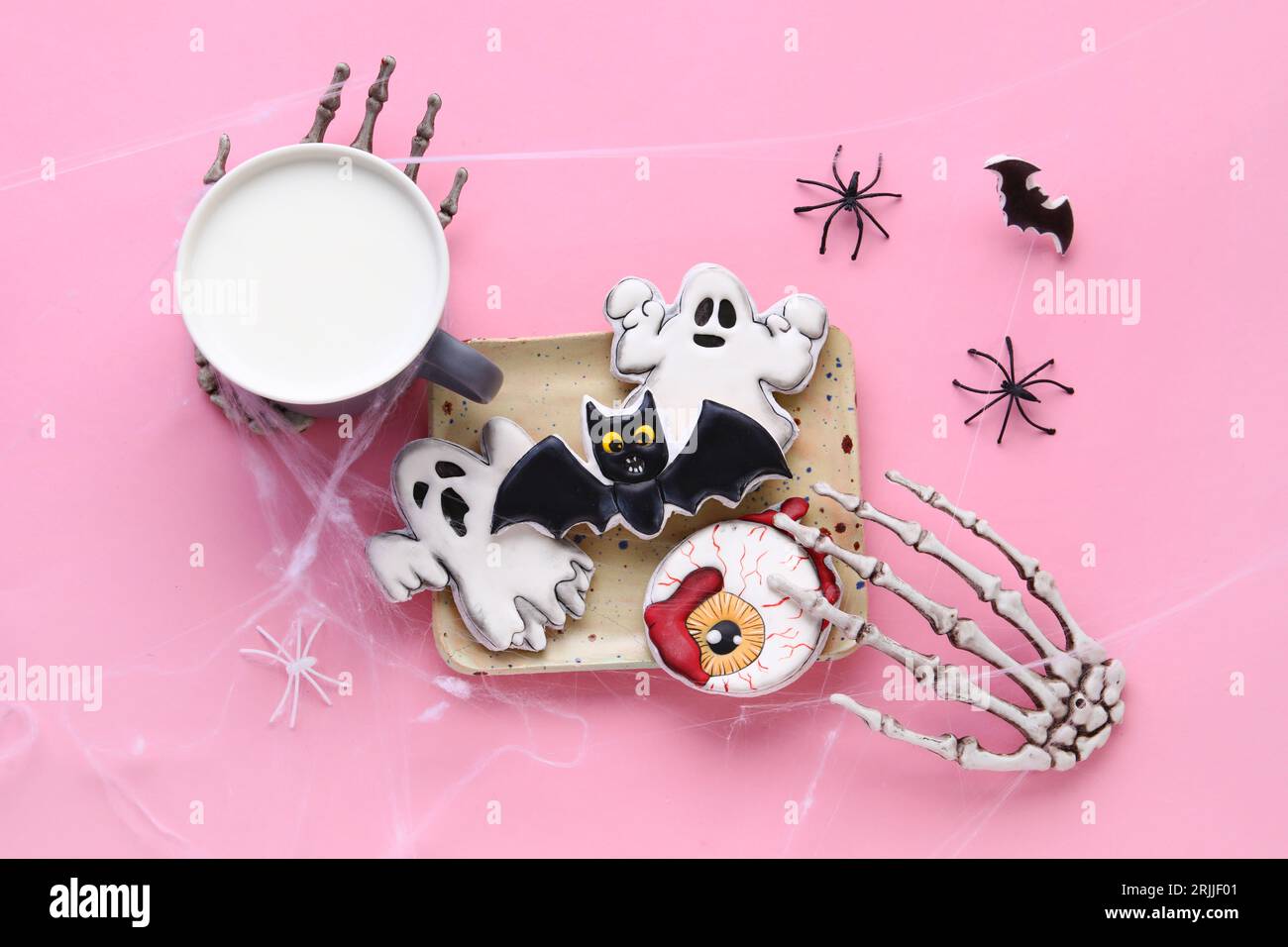 Plate with different tasty cookies, cup of milk and skeleton hands for ...