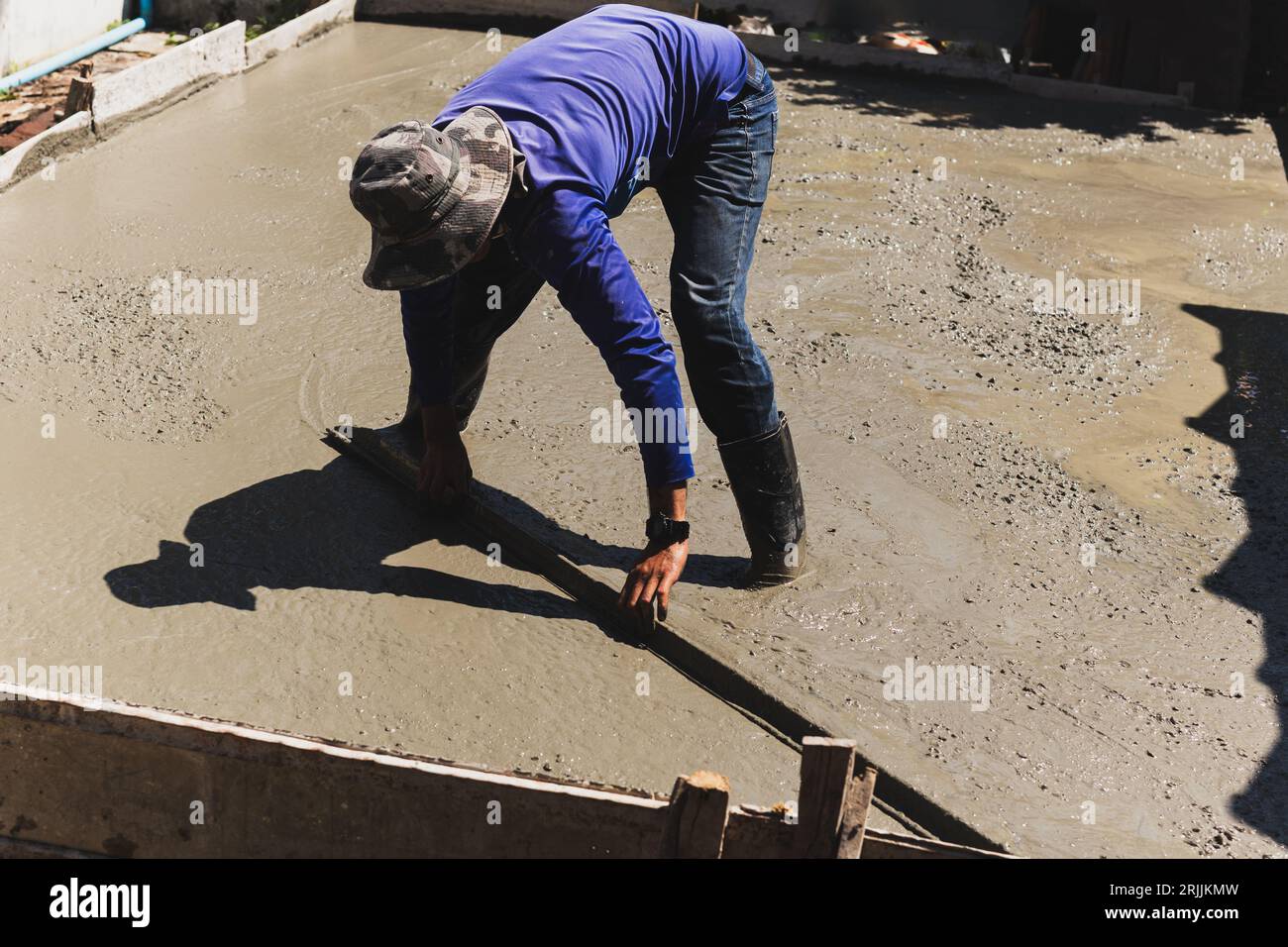 Workers level cement concrete concrete patio floor using long trowel ...