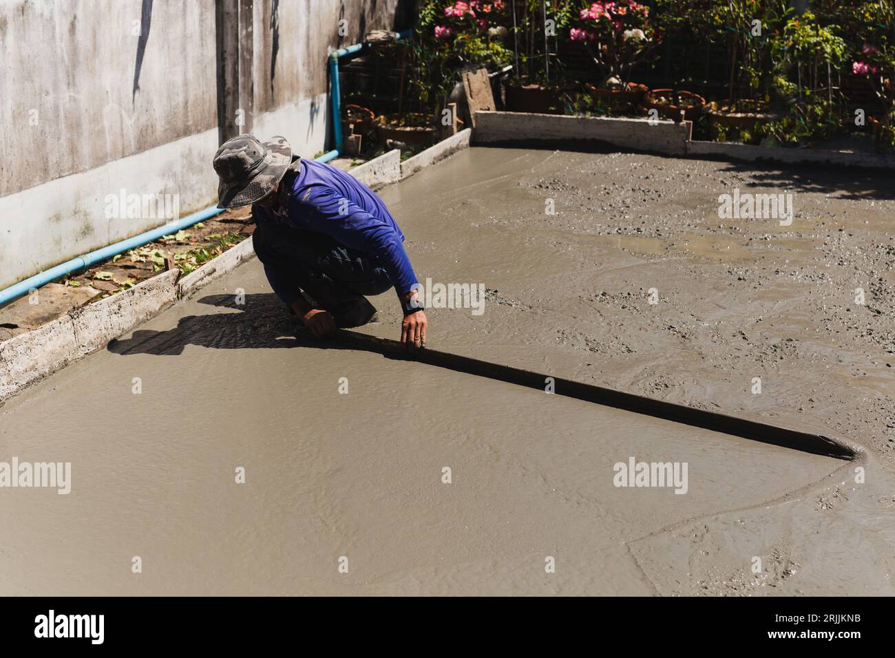 Workers level cement concrete concrete patio floor using long trowel ...