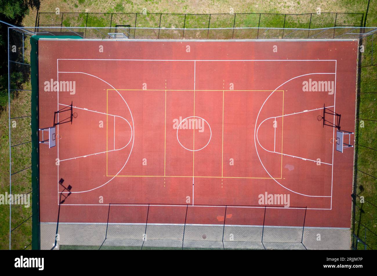 An aerial view of an empty basketball court, illuminated by the sun's ...