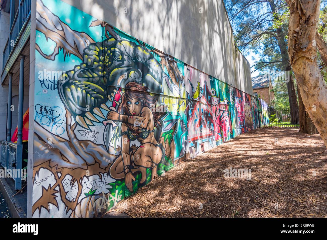 A Street art mural on the side of a building and beside an urban park ...