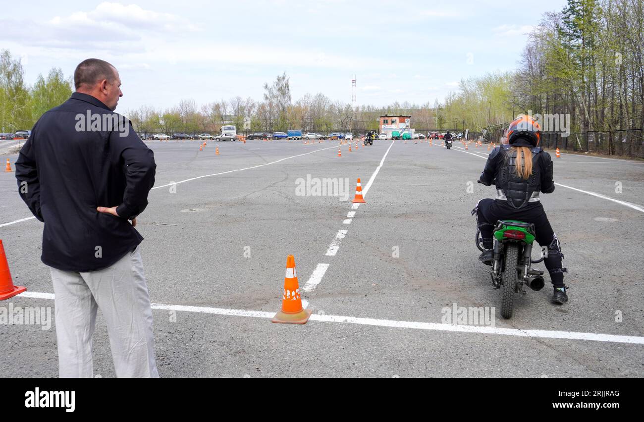 A young woman is learning to ride a motorbike in a motorcycle school ...