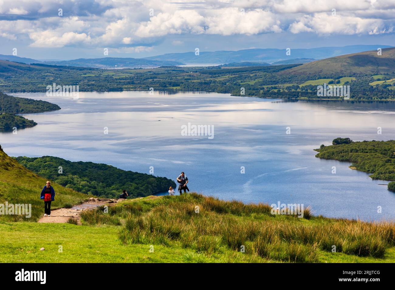 Hikers and walkers descending Conic Hill overlooking Balmaha and Loch ...